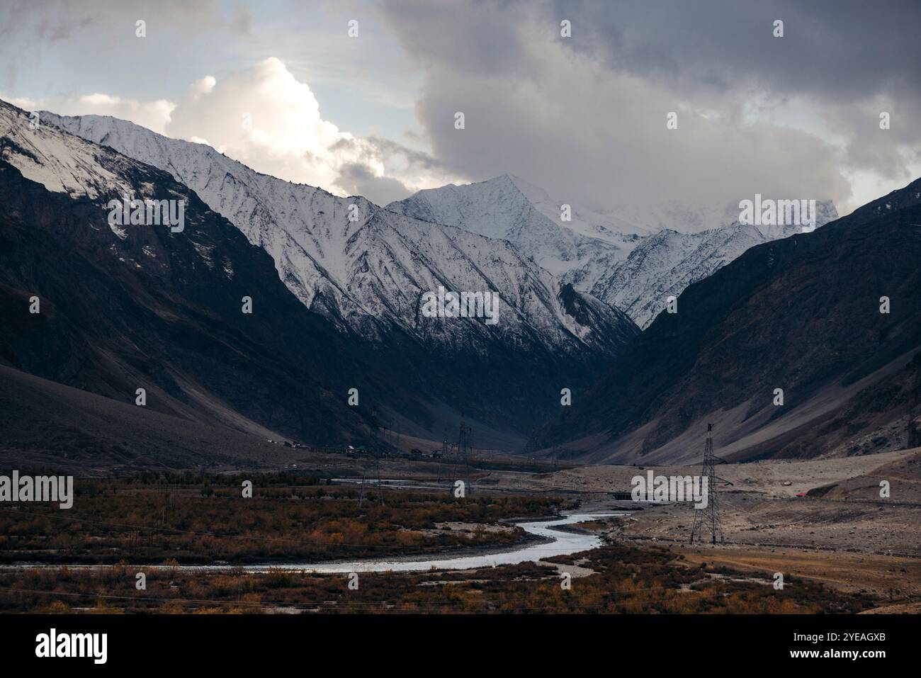 Valley with a river and electric pylons and powerlines, and snow-capped ...