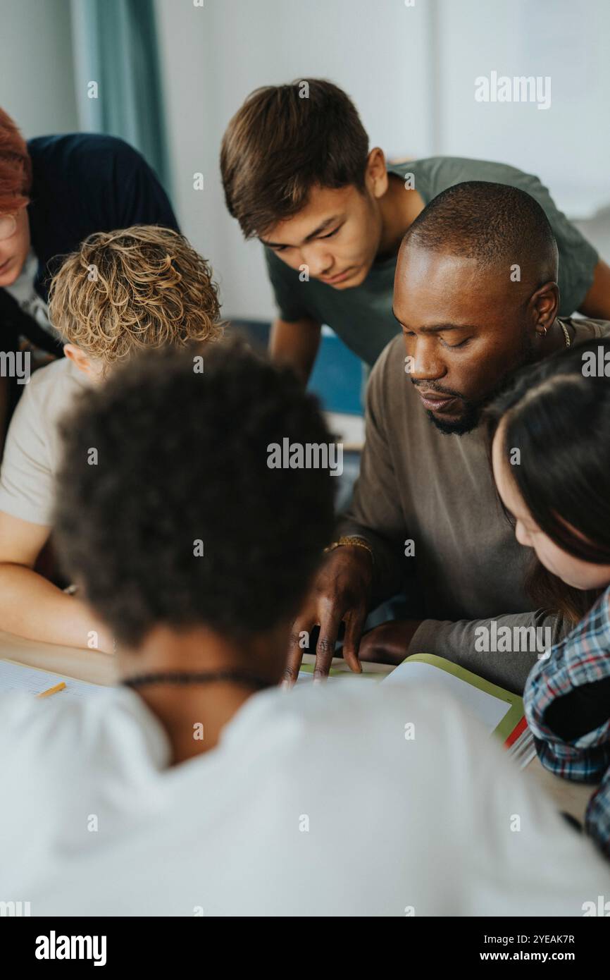 Male teacher discussing with high school students in classroom Stock ...