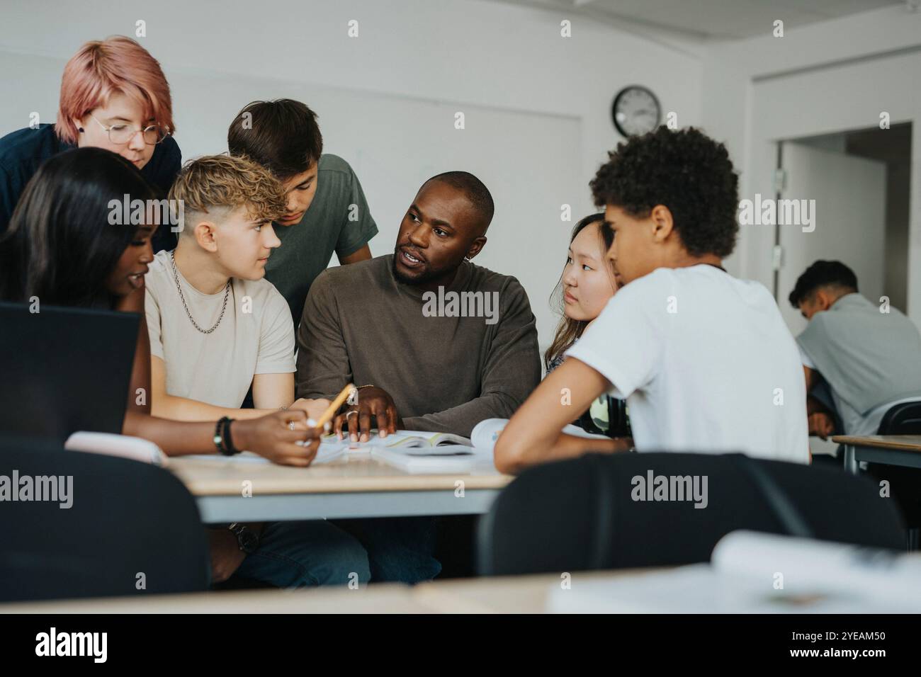 Male teacher teaching boys and girls with non-binary person in ...