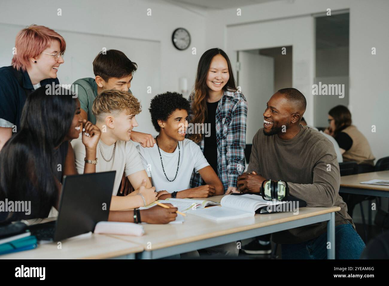 Happy male and female students with non-binary person discussing with ...
