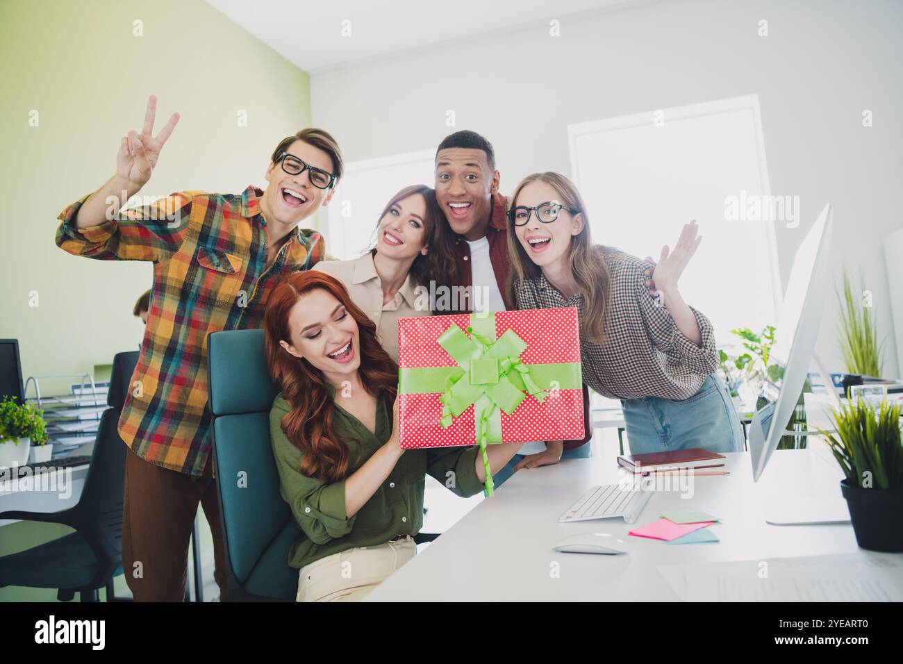 Photo of smiling happy web designers showing v-sing giving present box ...