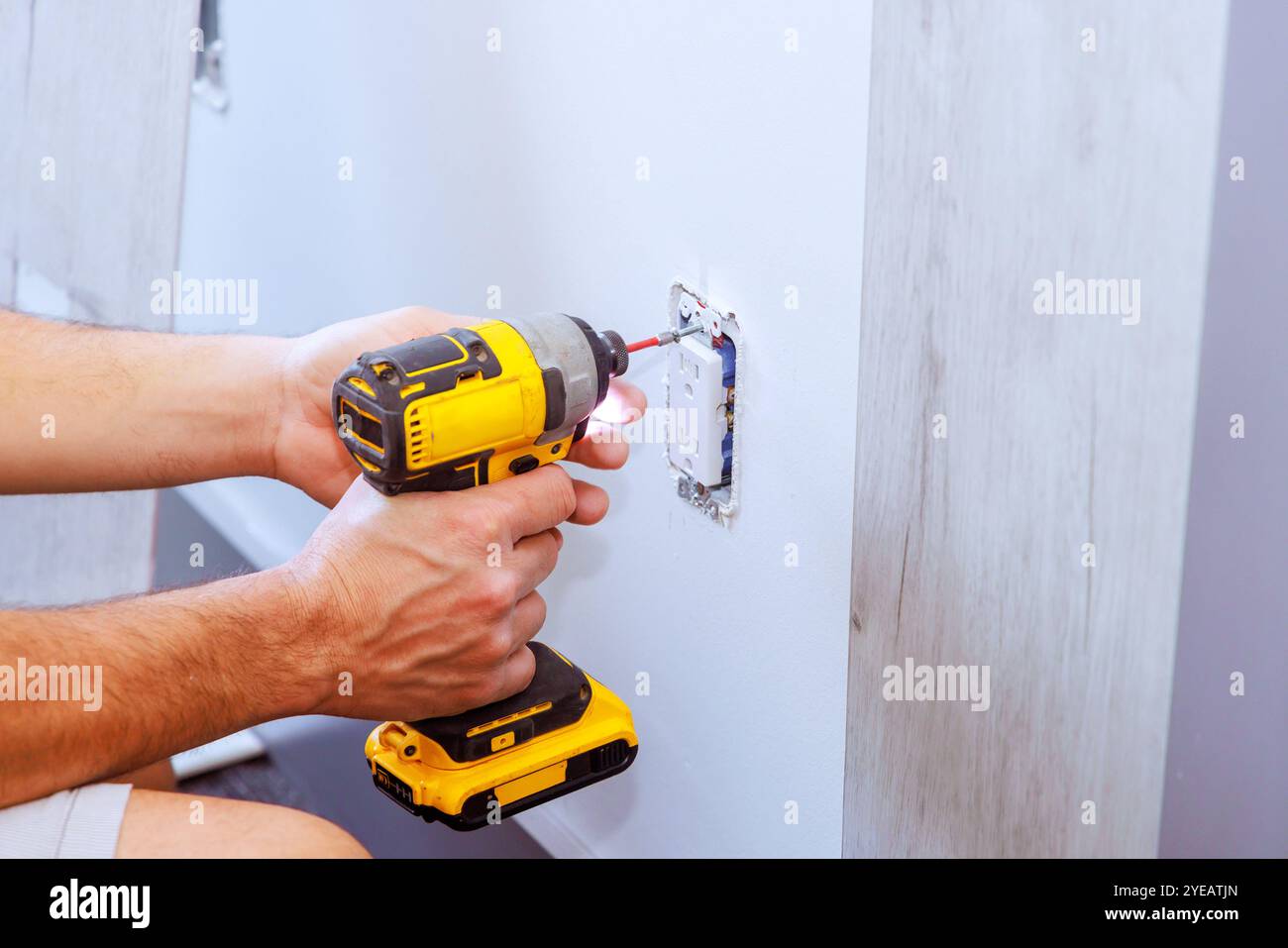 Electrician installs an outlet at wall using screwdriver during ...