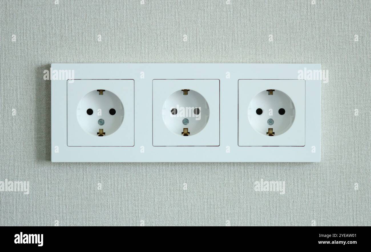Electrical sockets in a triple plastic frame against the background of ...