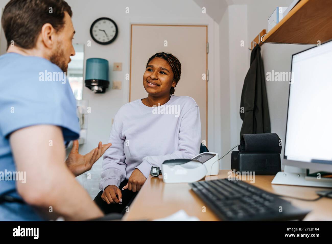 Male doctor explaining young women while sitting near table at medical ...