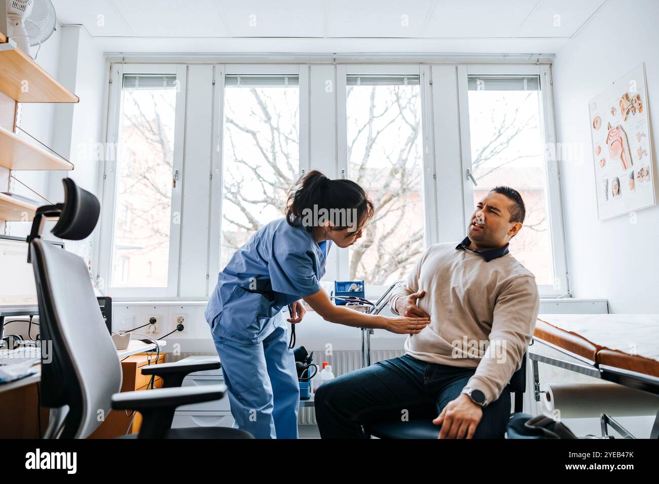Female healthcare worker examining stomachache of male patient in ...