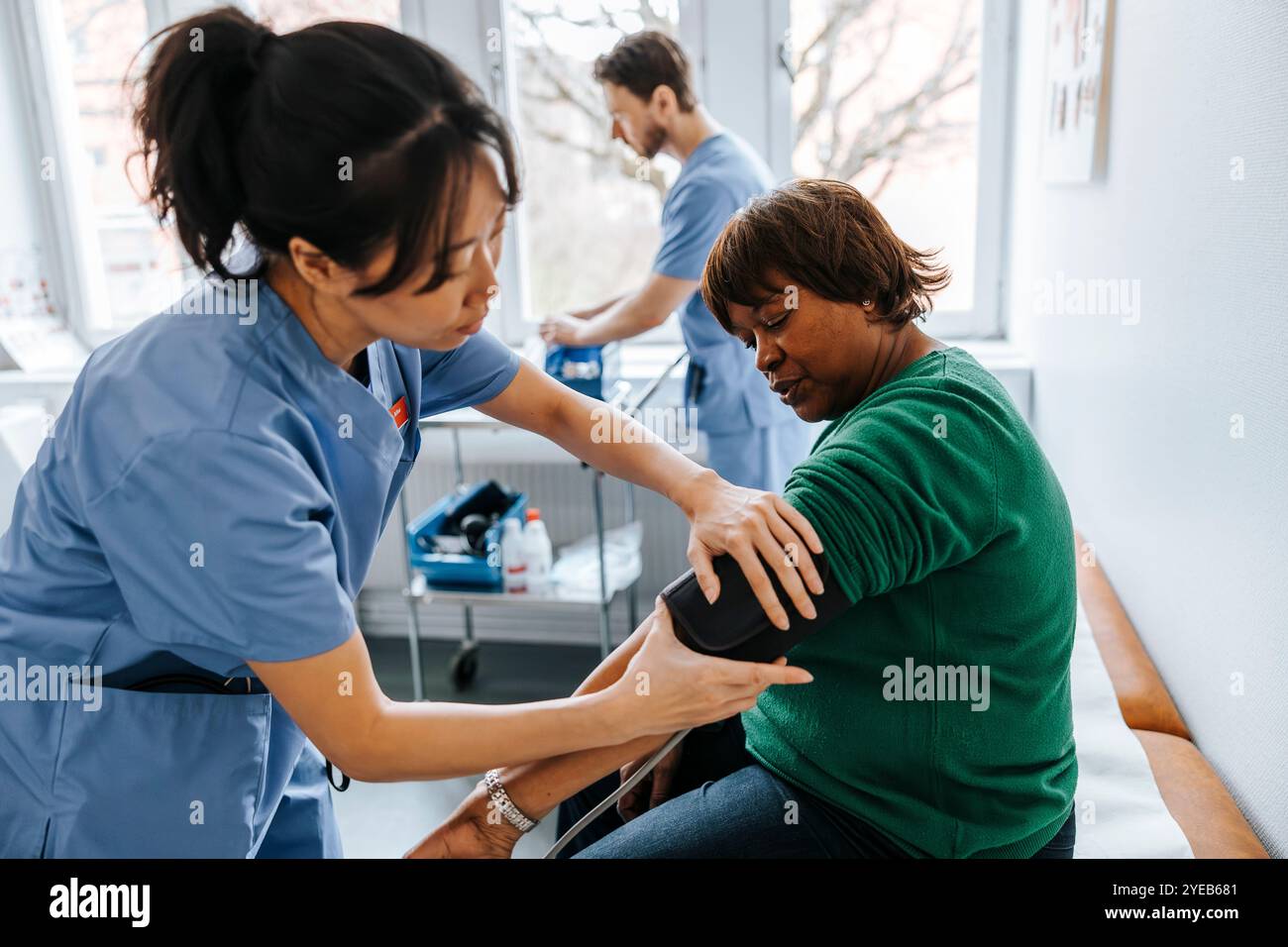 Female healthcare worker checking senior patient's blood pressure in ...