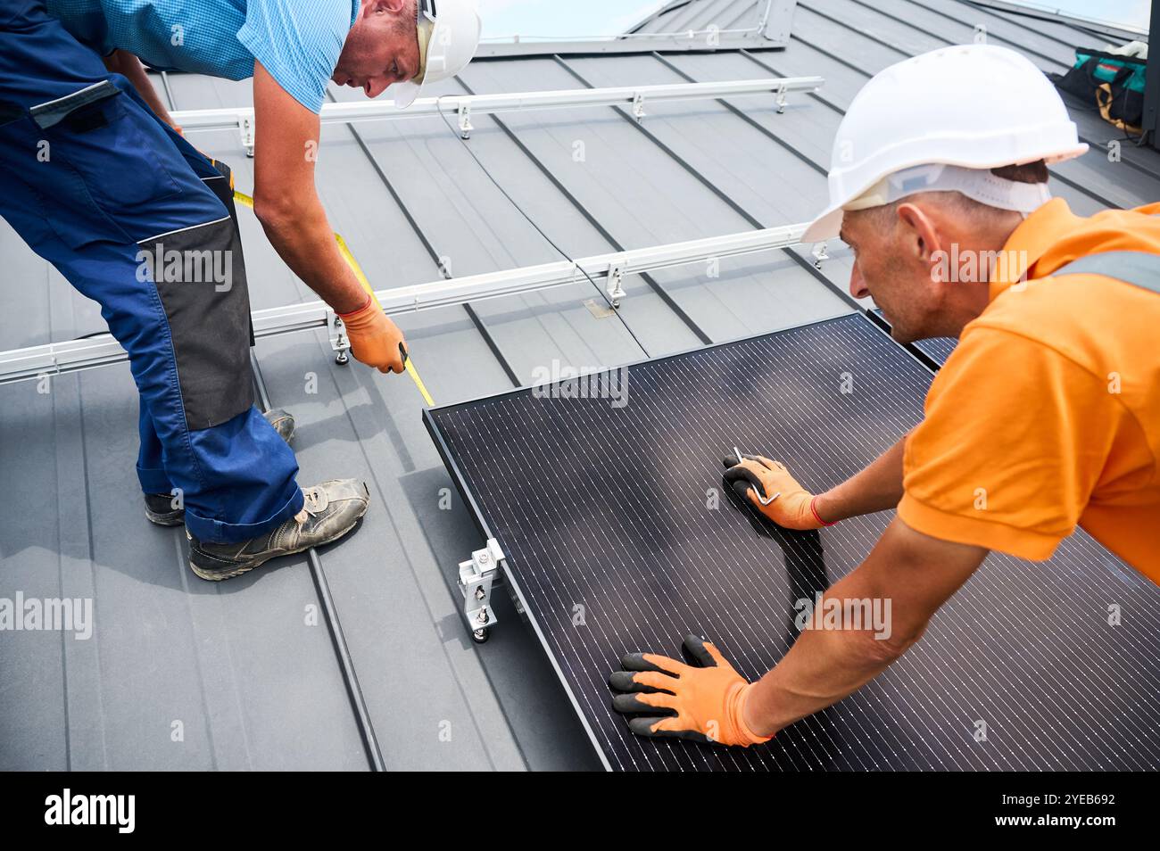 Workers building solar panel system on rooftop of house for generating ...