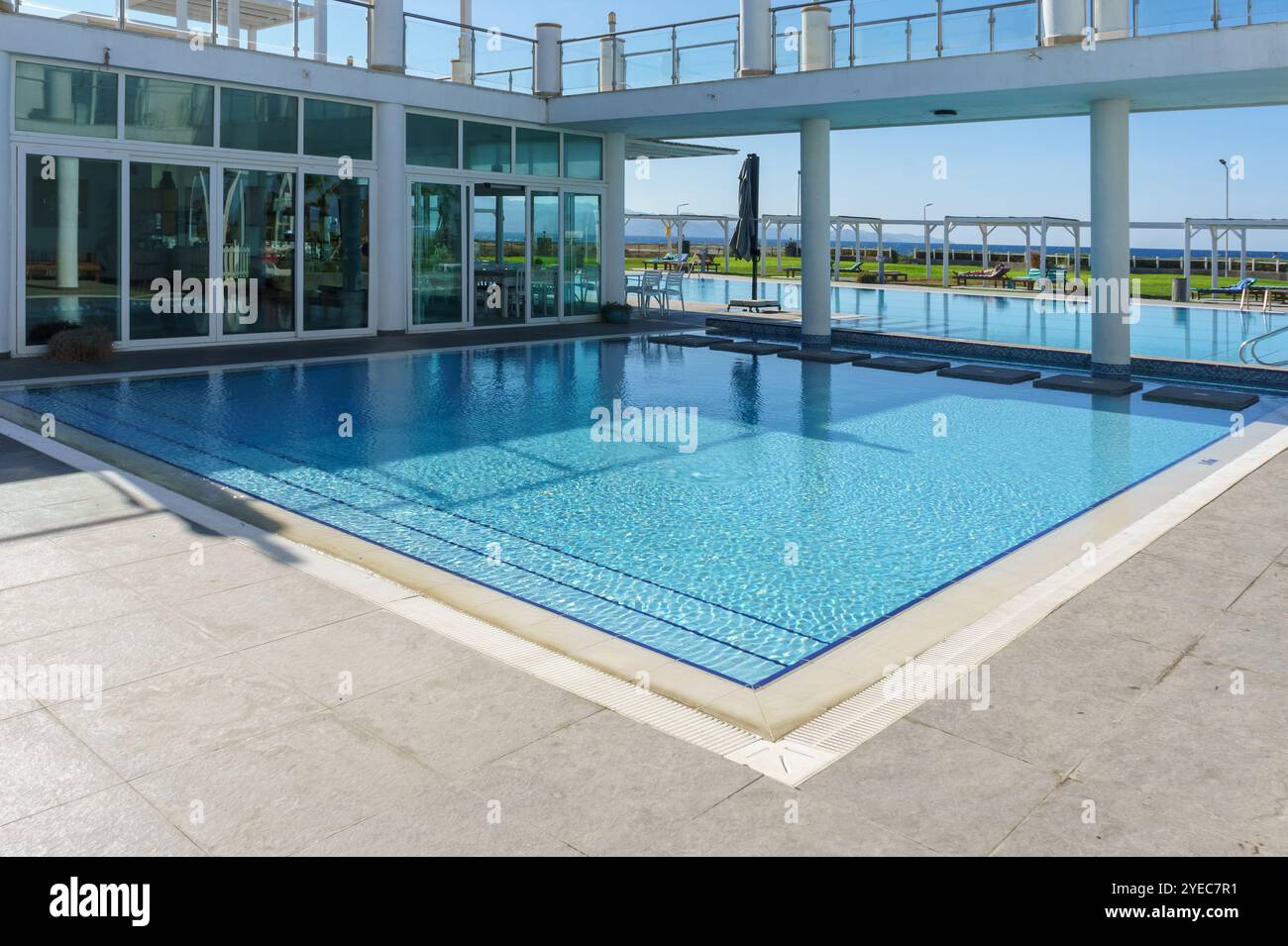 A tranquil swimming pool glistens under the sun, surrounded by ...