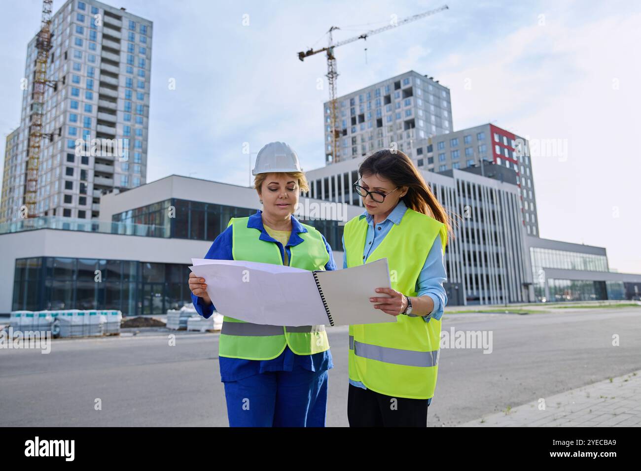 Two confident women talking working on construction of residential ...