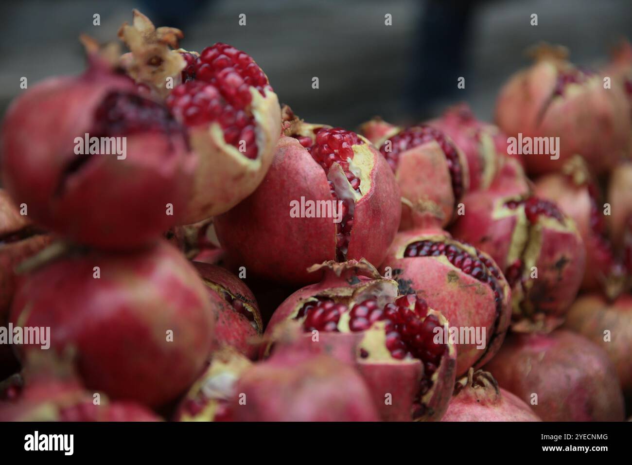 Rustic table with ripe, textured pomegranates, some split open to ...
