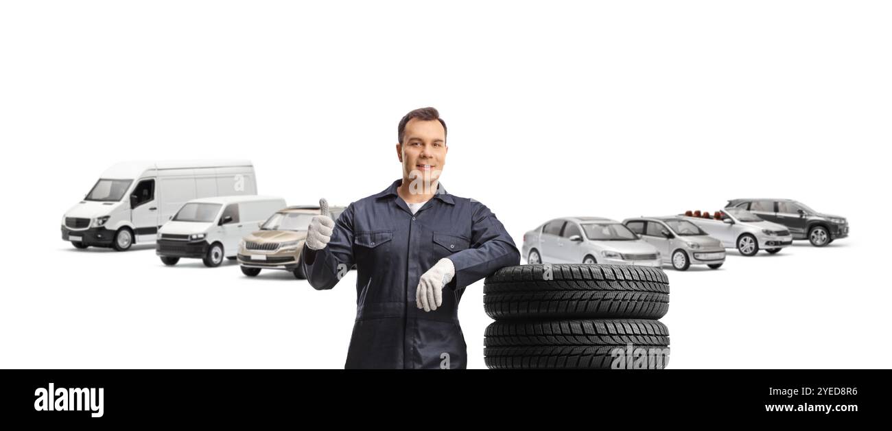 Auto mechanic worker in a uniform leaning on a pile of tires at a ...