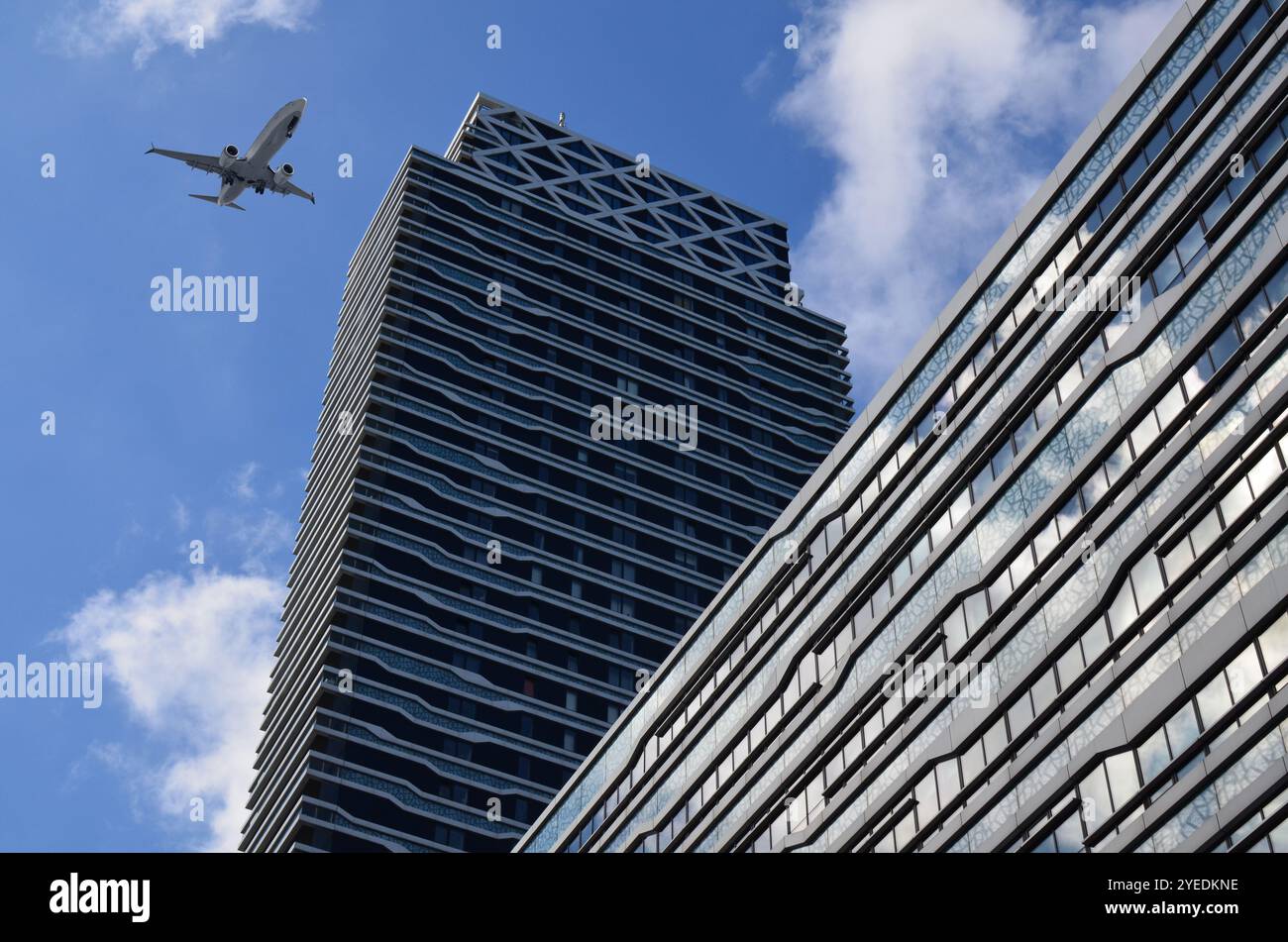 Airplane flying over buildings in city, low angle view Stock Photo - Alamy