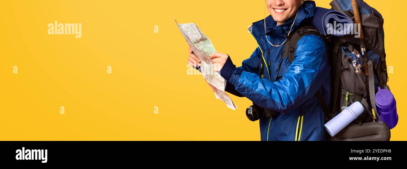 Backpacker following map, smiling over orange background Stock Photo ...
