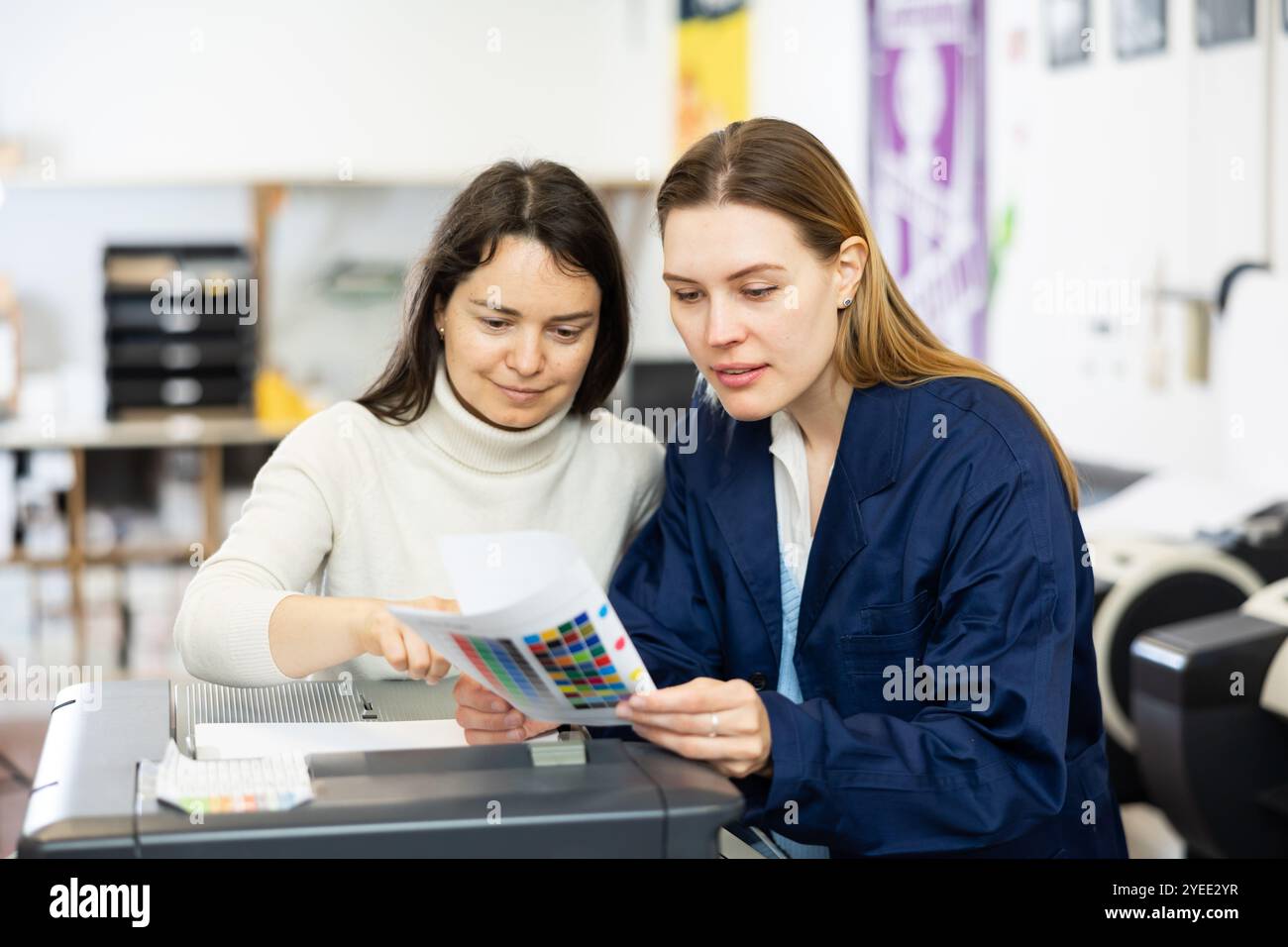 Female printshop workers talking about color test page Stock Photo - Alamy