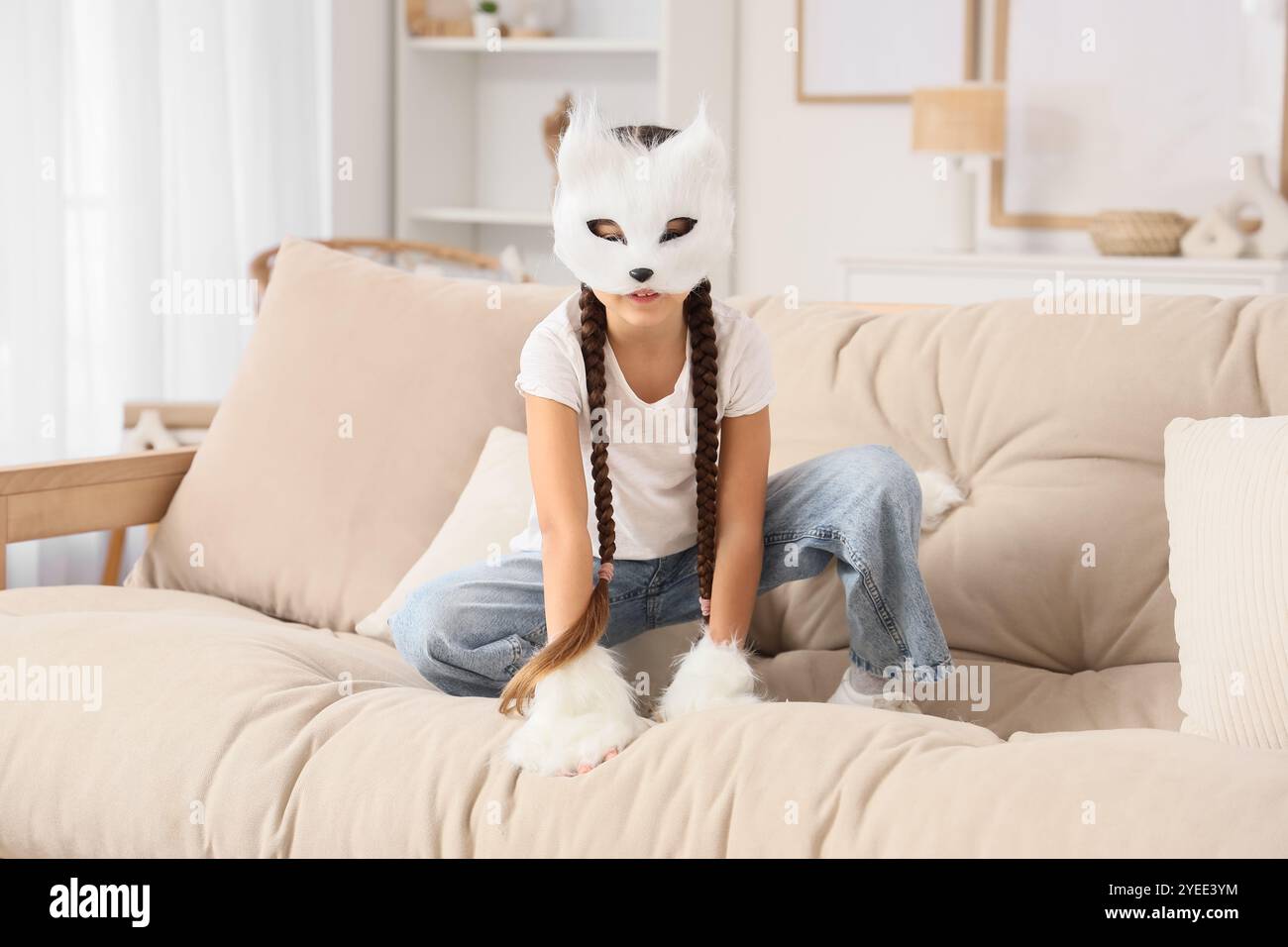Quadrober girl in cat mask sitting on sofa at home Stock Photo - Alamy