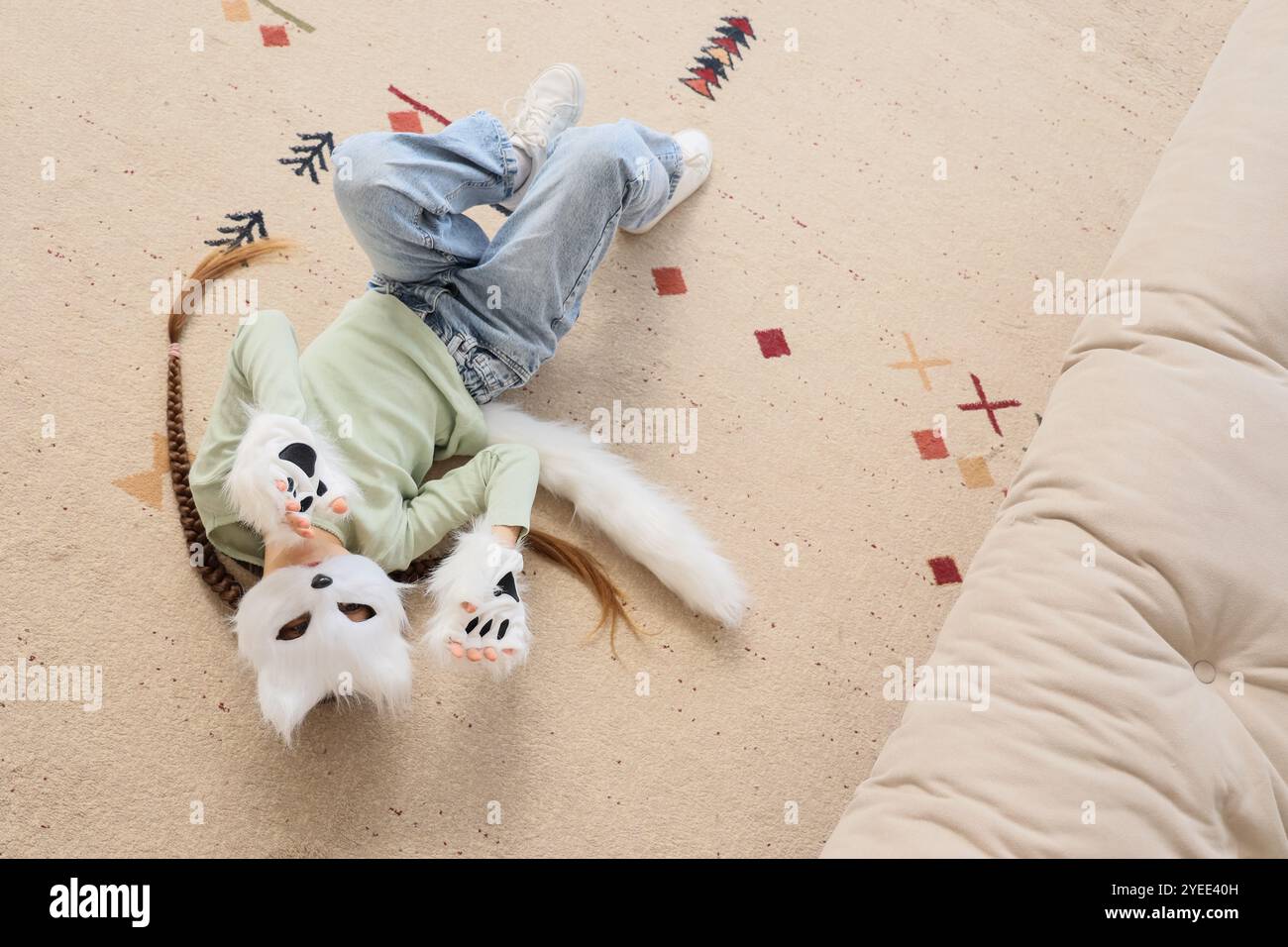 Quadrober girl in cat mask lying on carpet at home, top view Stock ...