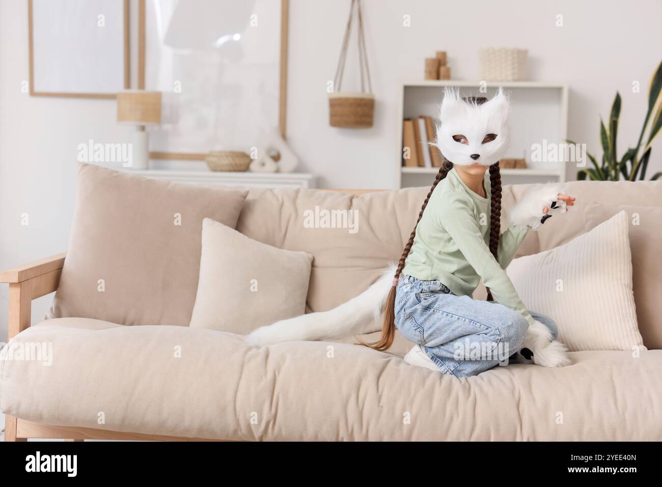 Quadrober girl in cat mask sitting on sofa at home Stock Photo - Alamy