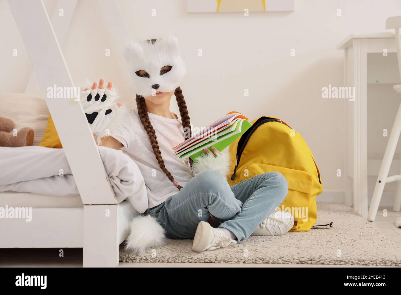 Quadrober girl with cat mask and copybooks sitting in bedroom Stock ...
