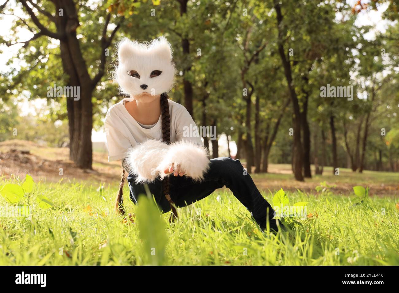 Quadrober girl with cat mask sitting on grass in park Stock Photo - Alamy