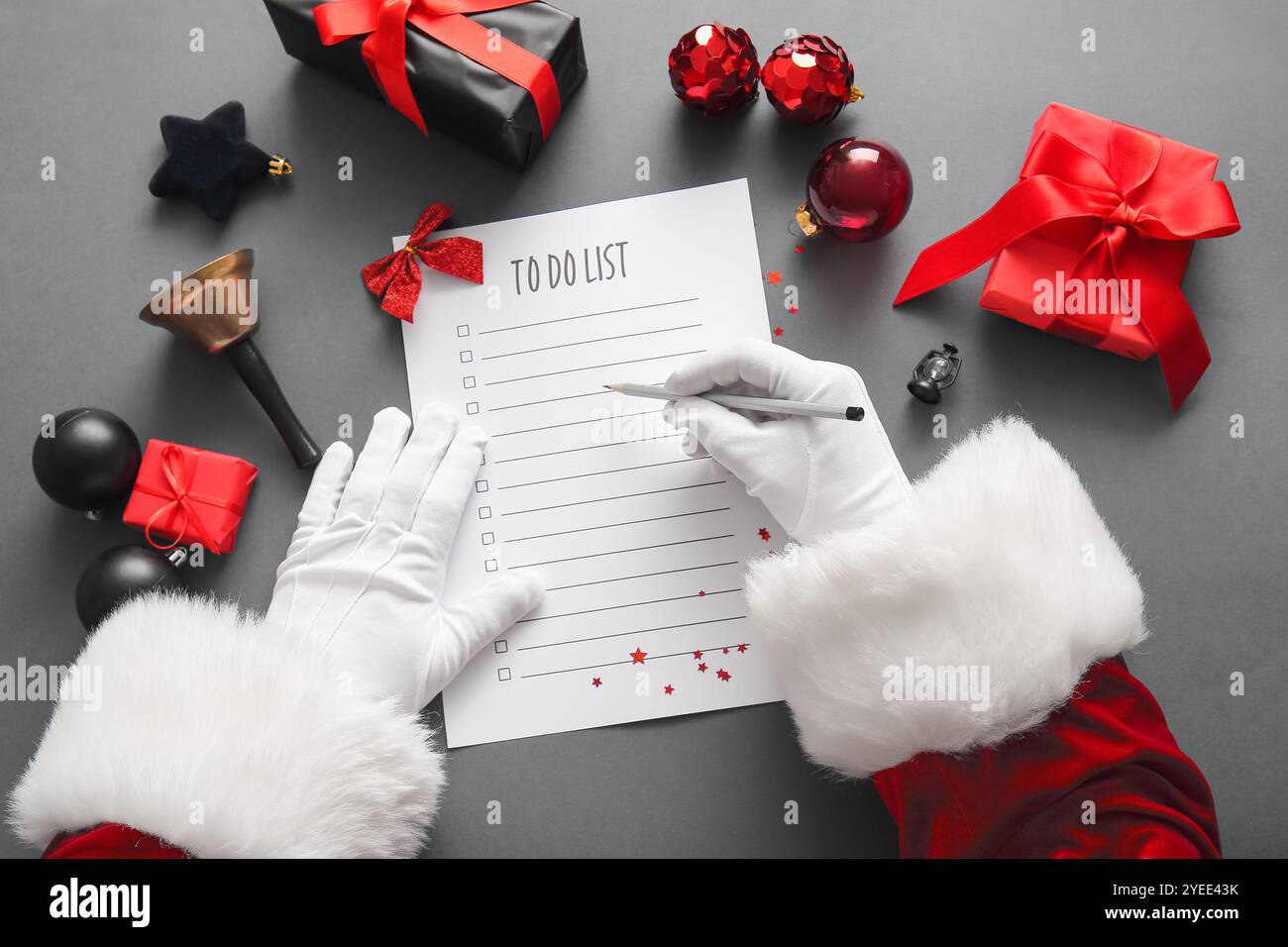 Santa Claus writing to-do list with Christmas decor on dark background ...