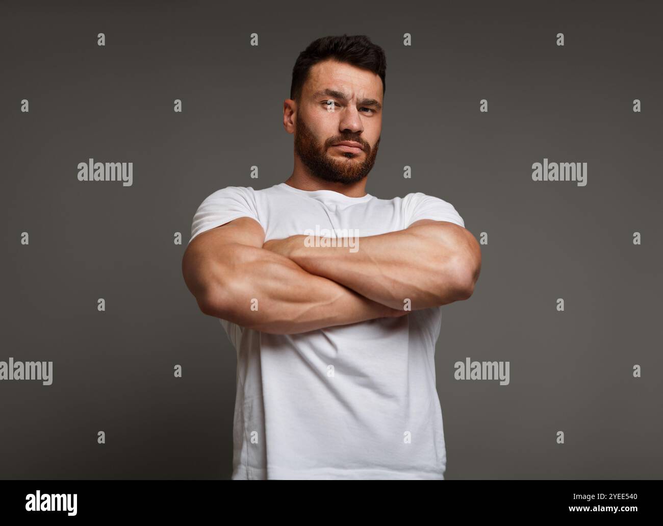 Suspicious young man with crossed big muscular arms Stock Photo - Alamy
