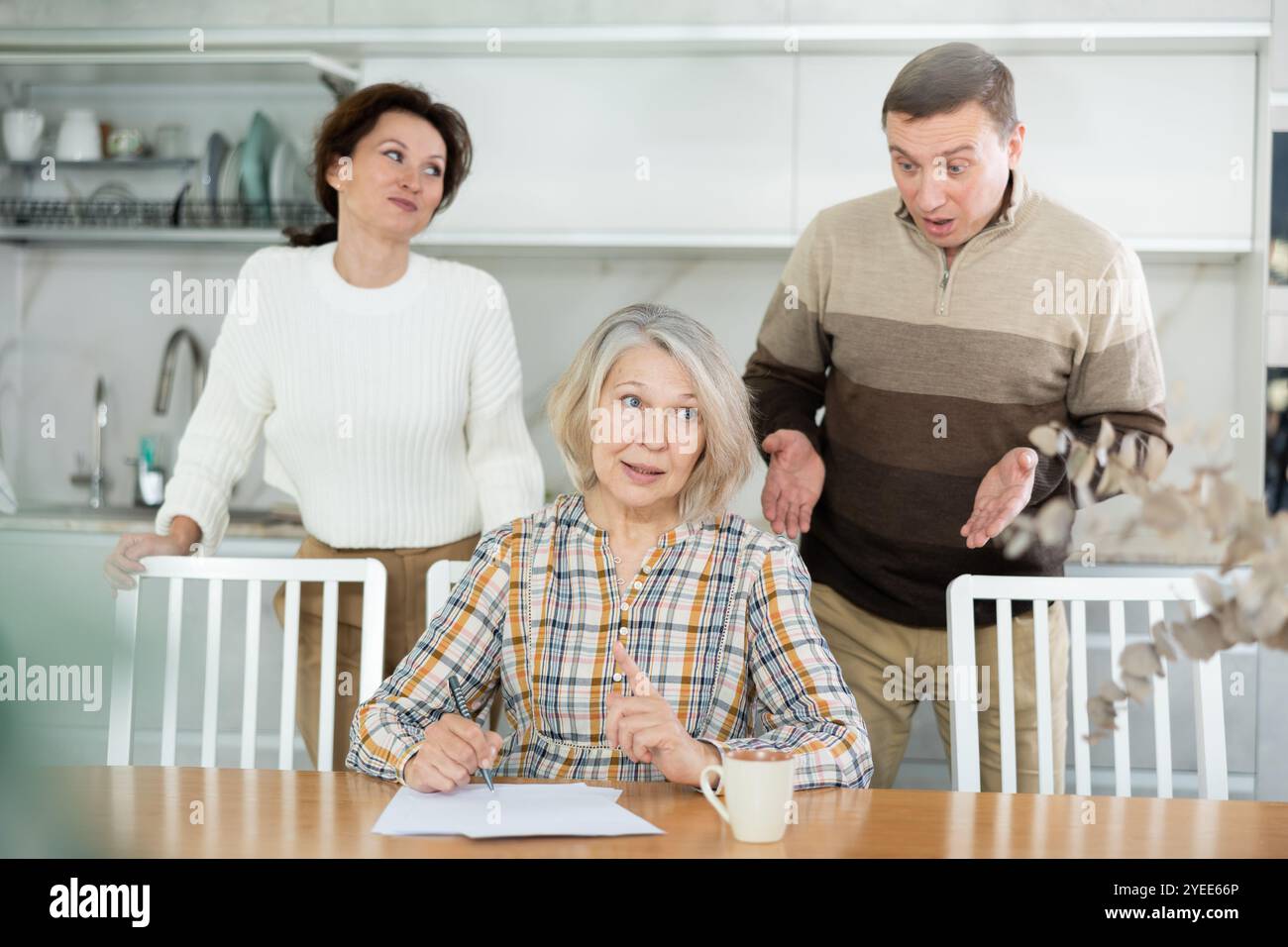 Old woman compiling heritage document while middle-aged man and woman ...