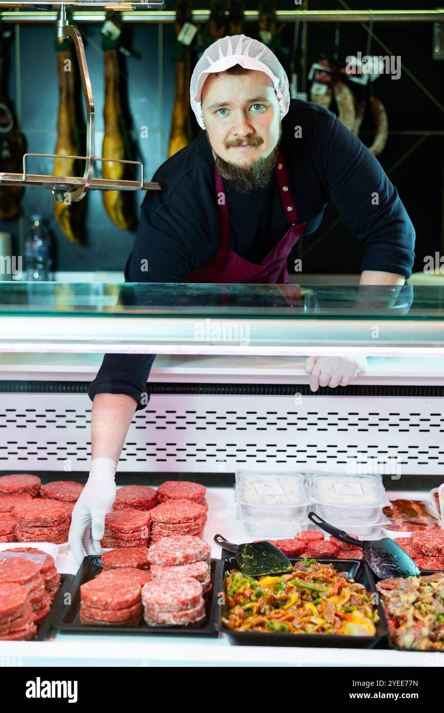 Man butcher holding meat cutlets in meat section of supermarket Stock ...