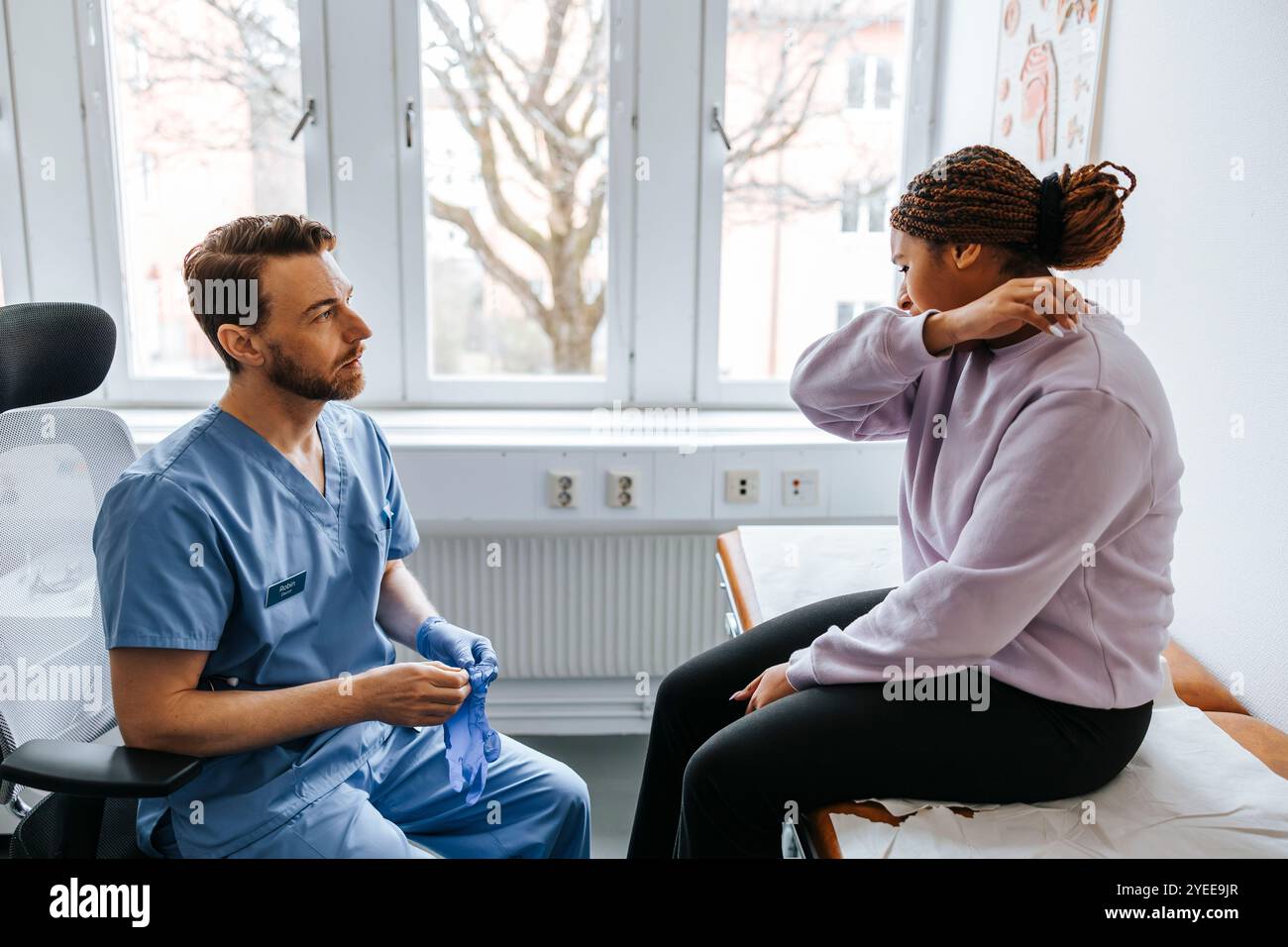 Young woman explaining problems while male doctor wearing gloves in ...