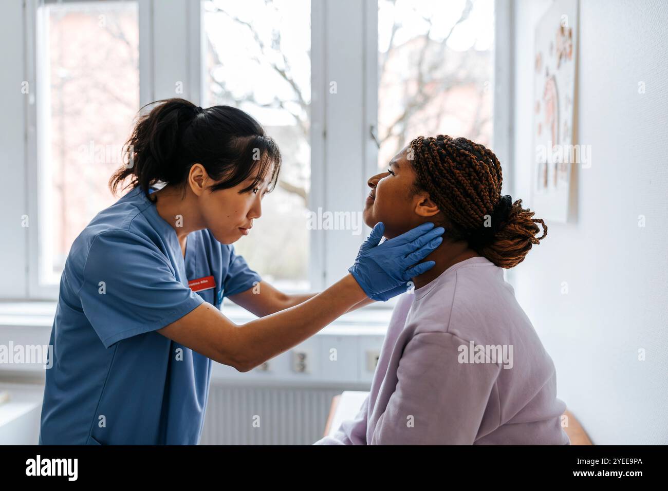 Focused female medical expert checking lymph nodes of young patient in ...
