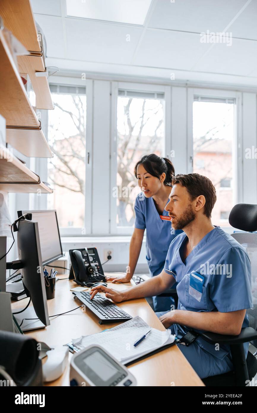 Focused male and female medical professionals working on computer in ...