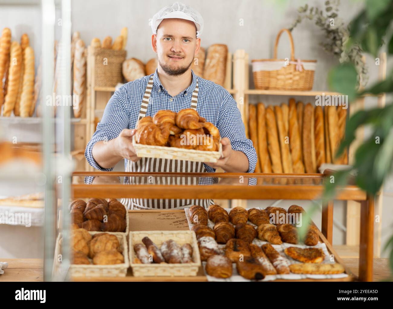 Selling fresh croissants in bakery - Baker places hot croissants on ...