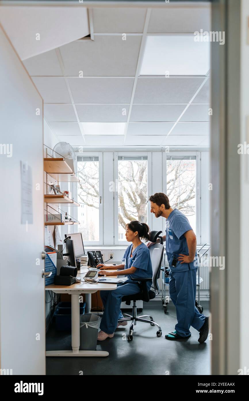 Female medical expert working on computer while male coworker standing ...