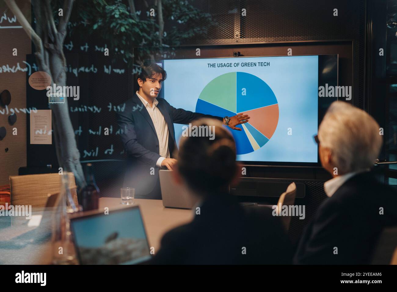 Young businessman explaining pie chart to male and female colleagues ...