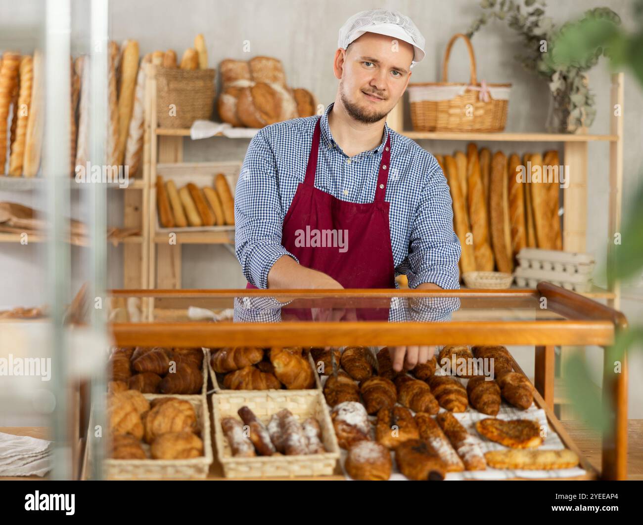 Selling fresh croissants in bakery - Baker places hot croissants on ...