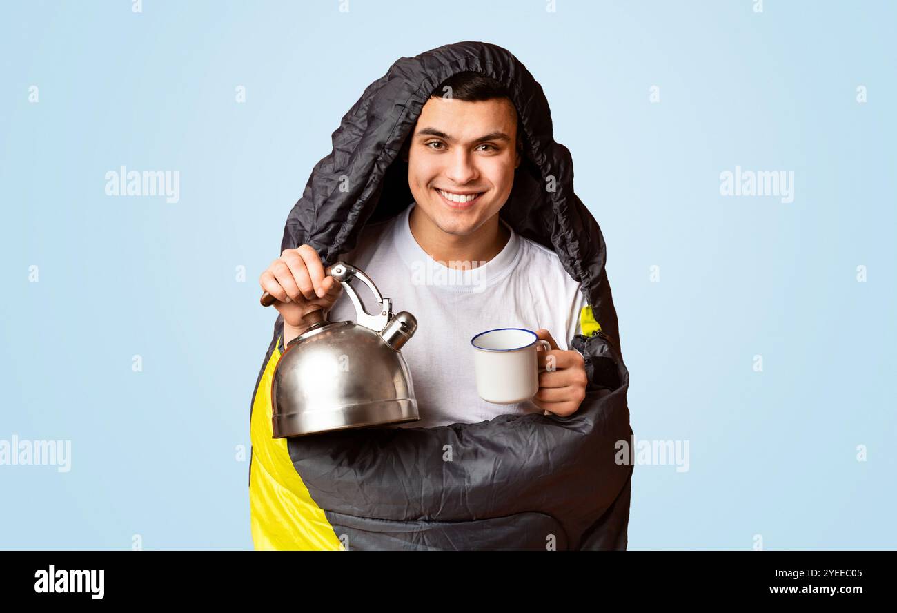 Happy tourist in sleeping bag drinking tea, holding pot Stock Photo - Alamy