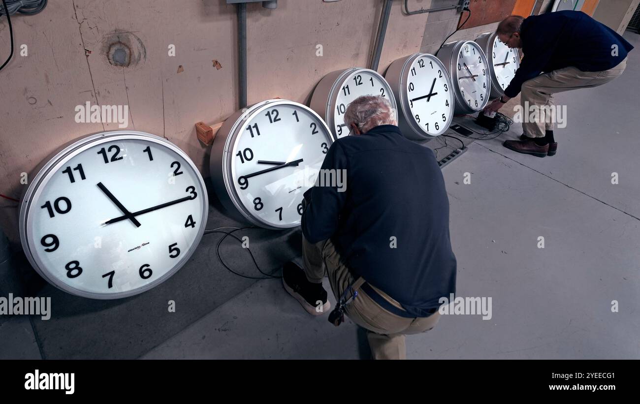 Clockmakers Rich Finn, left, and Tom Erb adjust the time zone ...