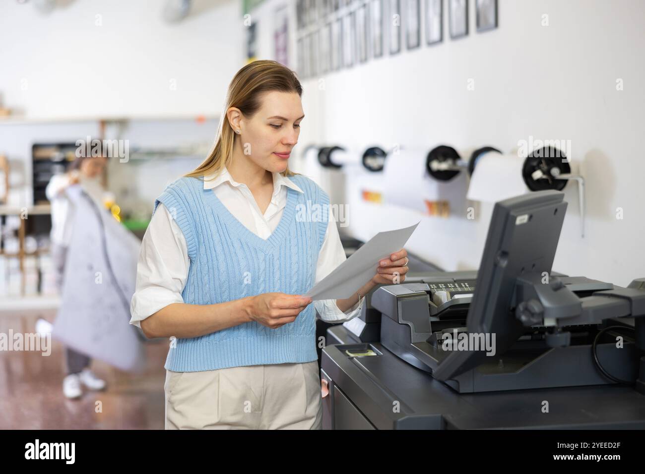 Woman checking paper after printing Stock Photo - Alamy