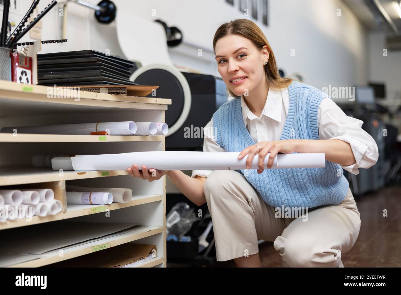 Woman employee at copy center putting roll paper on shelves Stock Photo ...