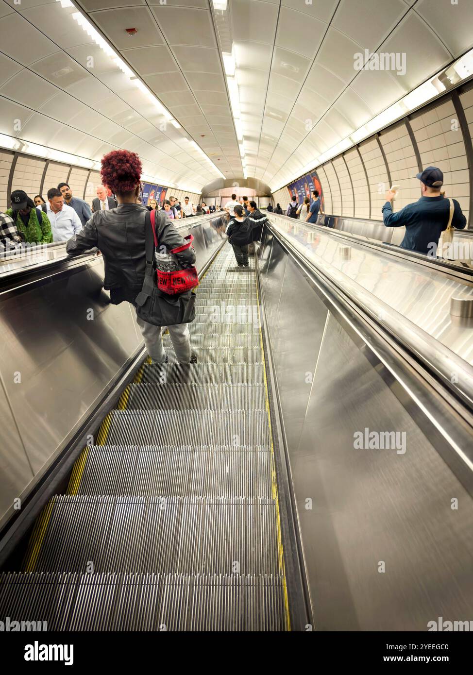 looking down on People riding an escalator inside a busy new york ...