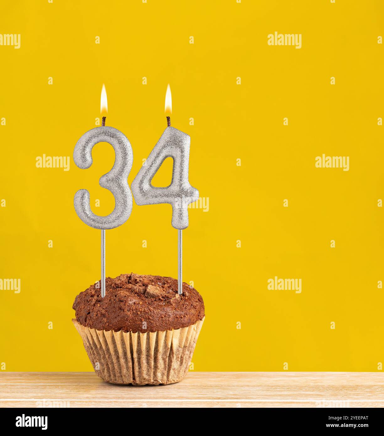 Chocolate cupcake with number 34 candle - Birthday on a yellow ...