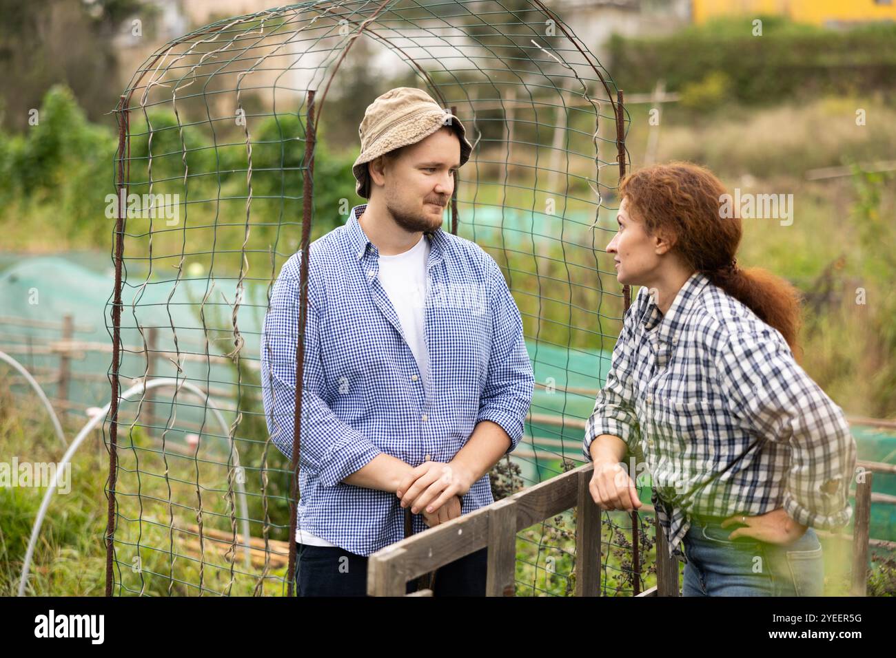 Female farmer friendly talking to her male neighbour on backyard on day ...