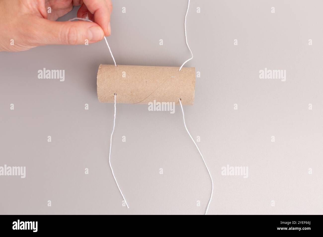 pair of hands working with empty toilet paper roll, threading a string ...