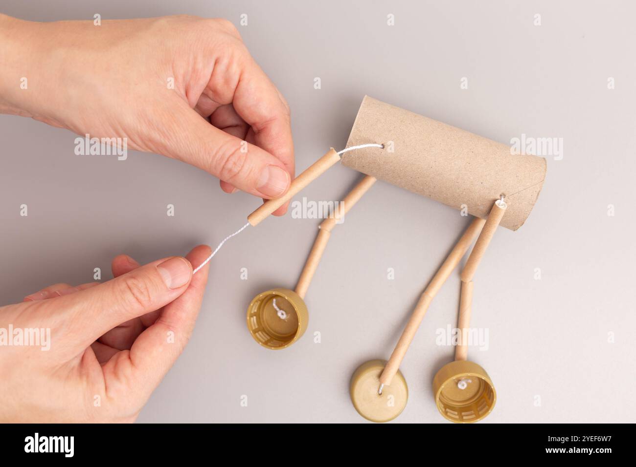 Hands assembling DIY reindeer puppet leg with cardboard tube, string ...