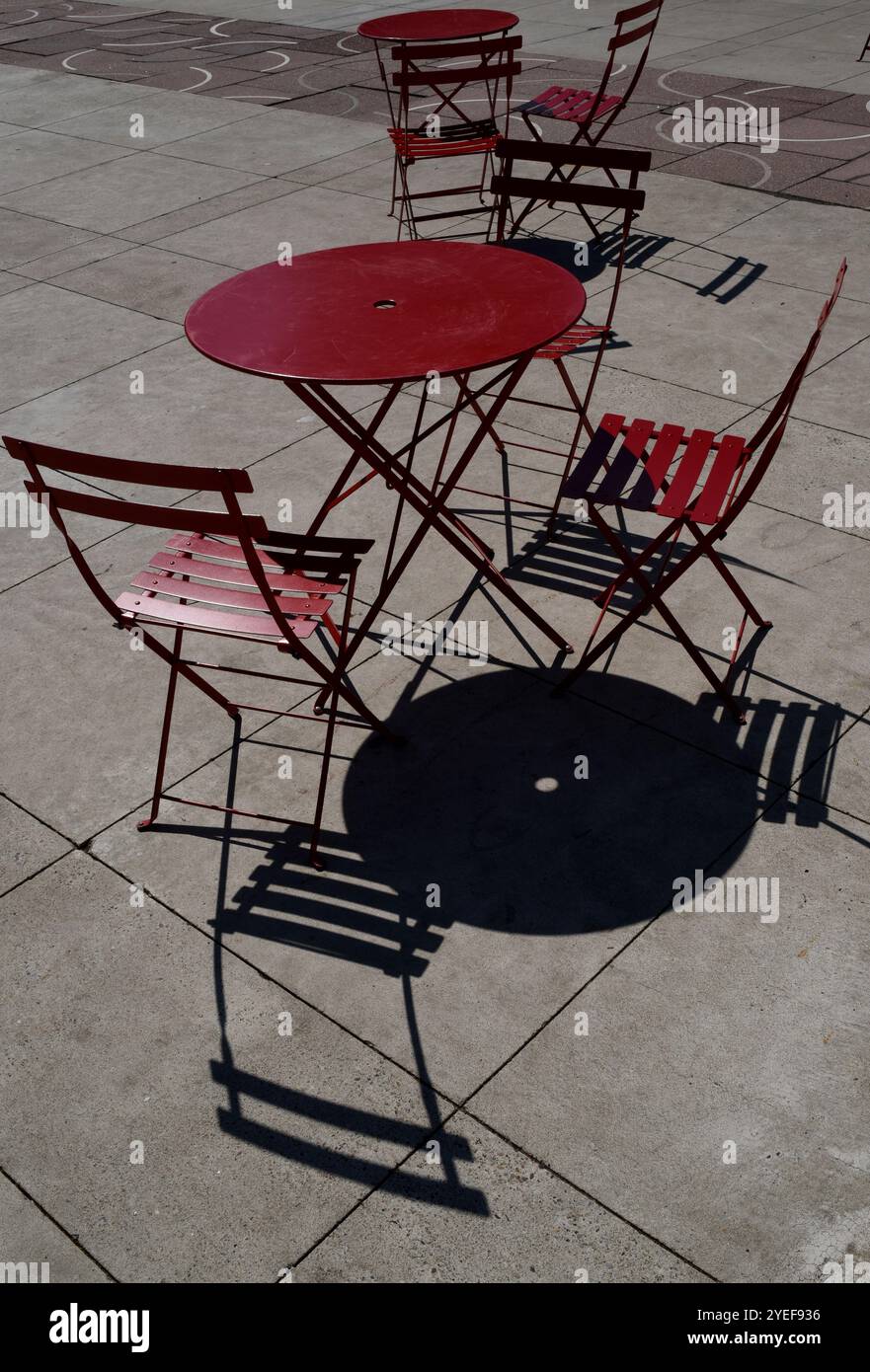 Maroon metal chairs and table cast shadows on a concrete plaza Stock ...