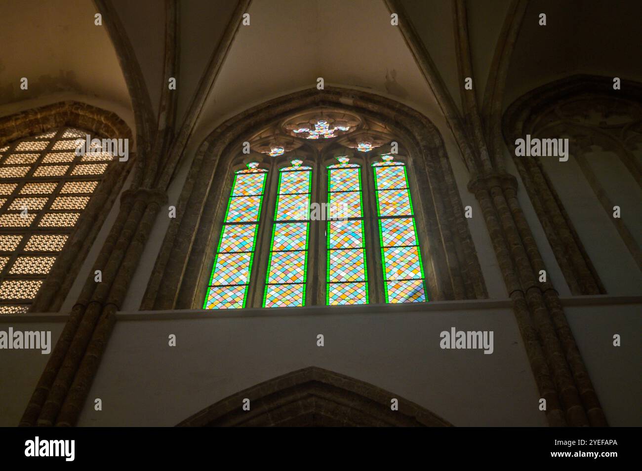 Colorful light streams through stained glass, casting enchanting reflections within the serene ...