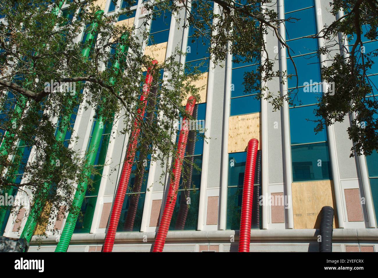 Tall modern Glass Building with temporary green and red AC duct tubes ...