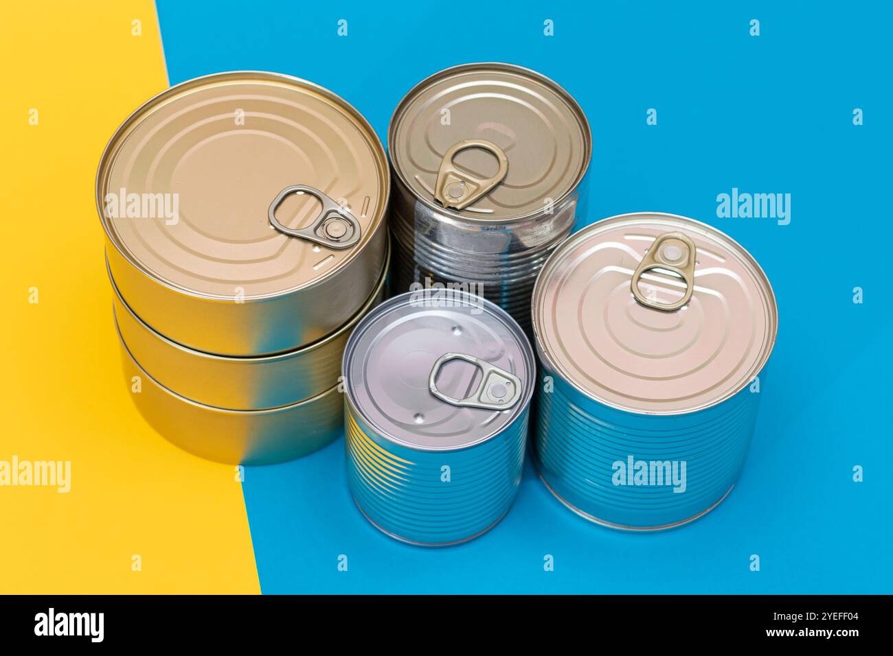A Group of Stacked Tin Cans on Split Blue and Yellow Background. Canned ...