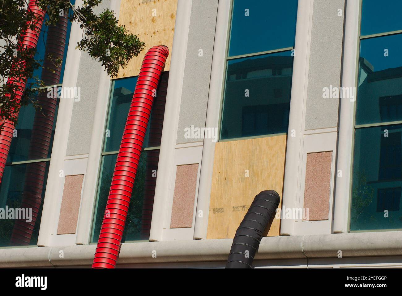 Tall modern Glass Building with temporary green and red AC duct tubes ...