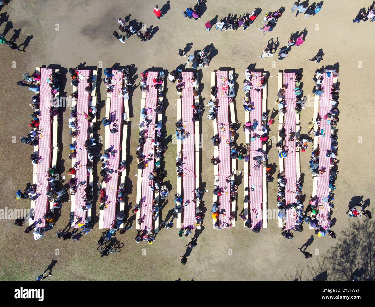 Tables with checkered tablecloths seen from above with people eating at ...