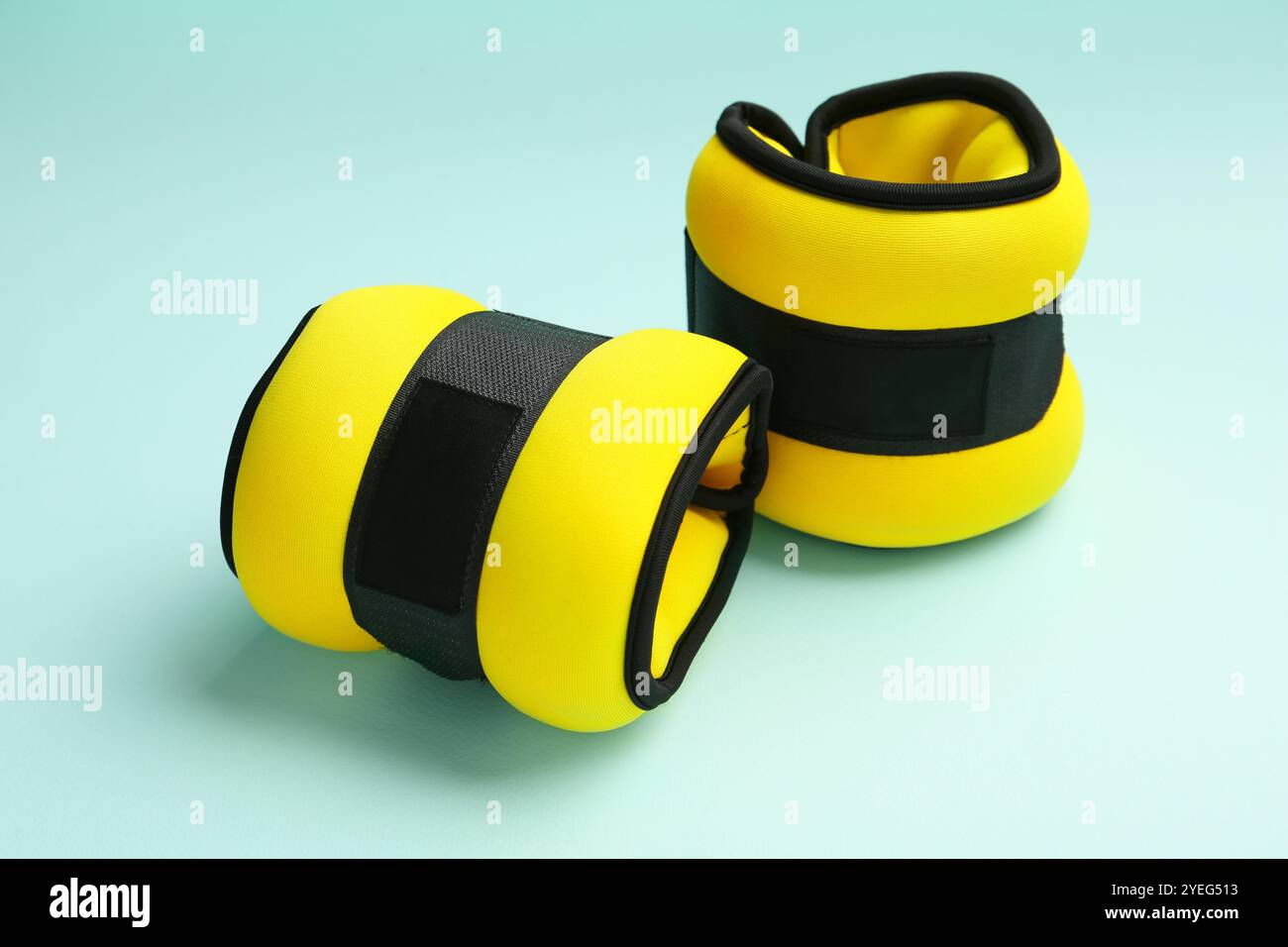Stylish yellow ankle weights on turquoise background Stock Photo - Alamy